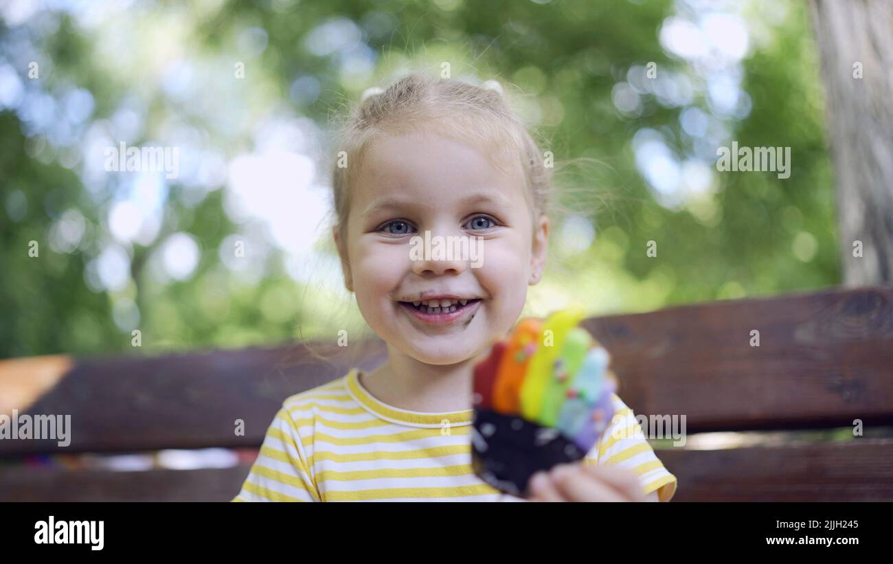 Little girl holds a multi-colored gingerbread and smiles. Close-up ...