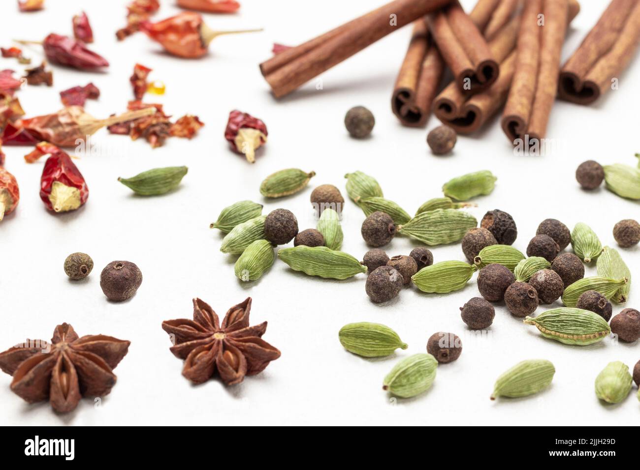 Allspice among cardamom seeds, star anise and cinnamon sticks. Close up ...