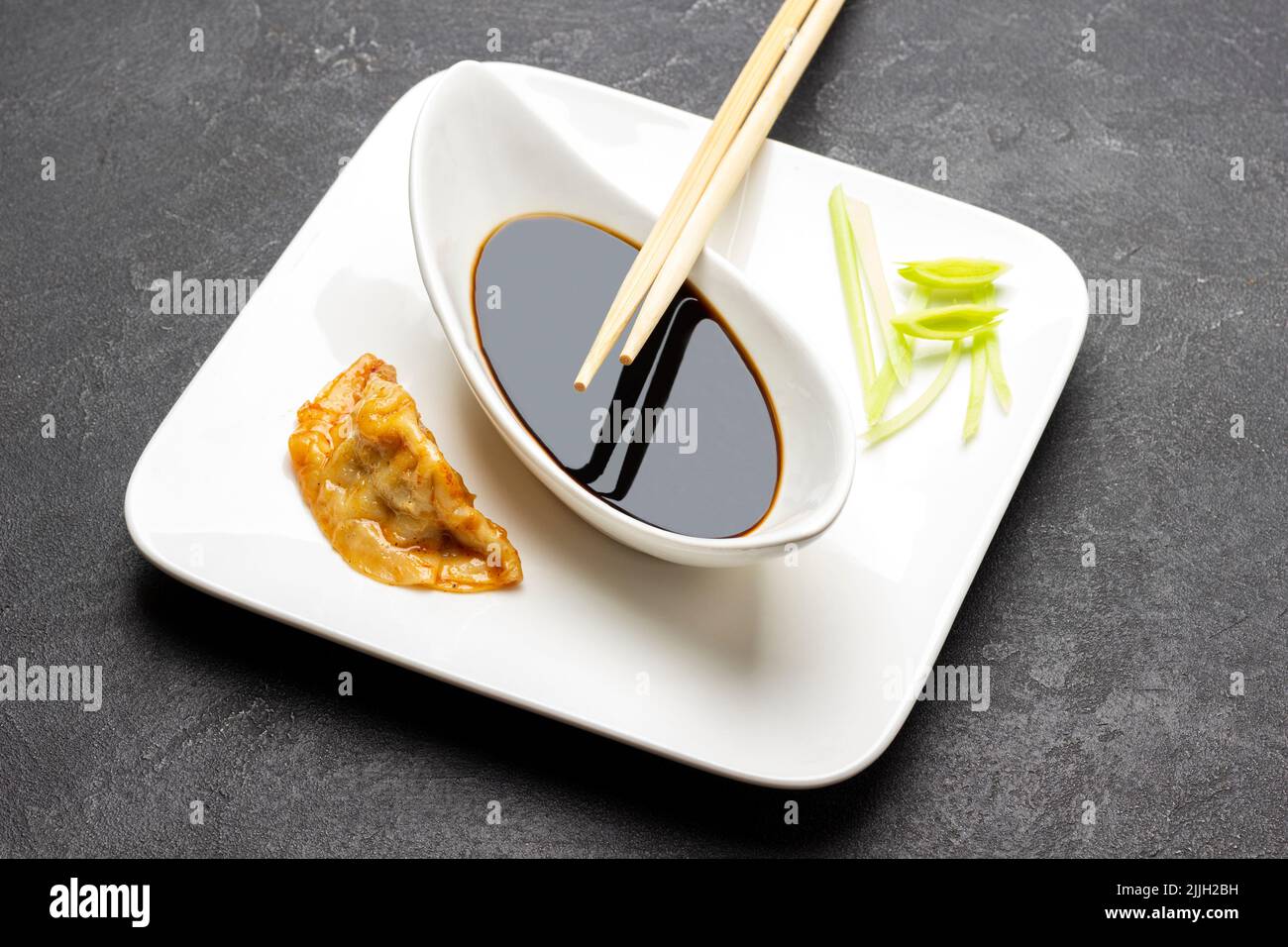 Chopsticks on white plate with soy sauce. Boiled gyoza dumpling and ...