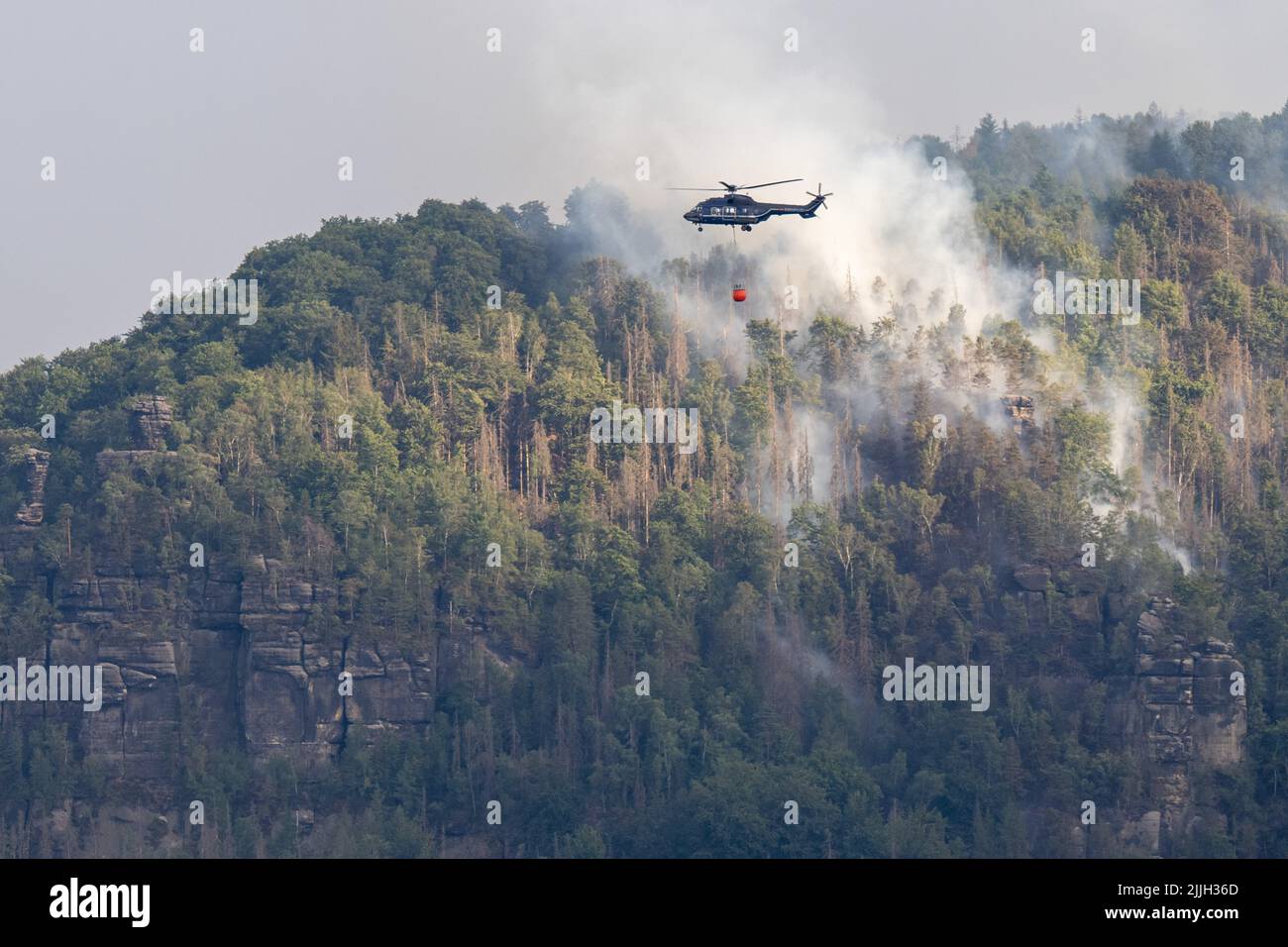 Schmilka, Germany. 26th July, 2022. A helicopter flies over a fire in ...
