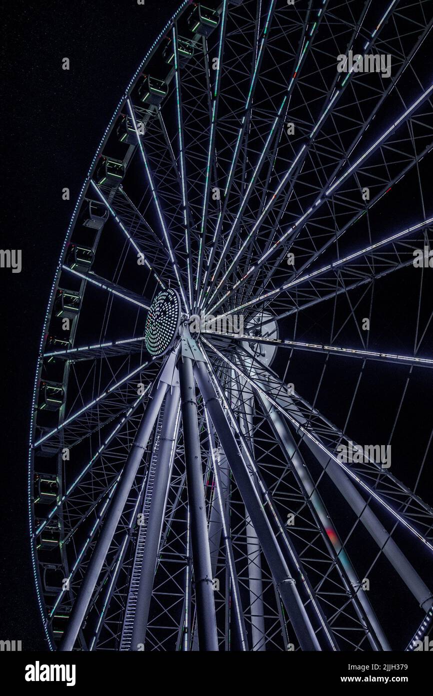 The low-angle view of the gray ferris wheel amusement ride at night ...