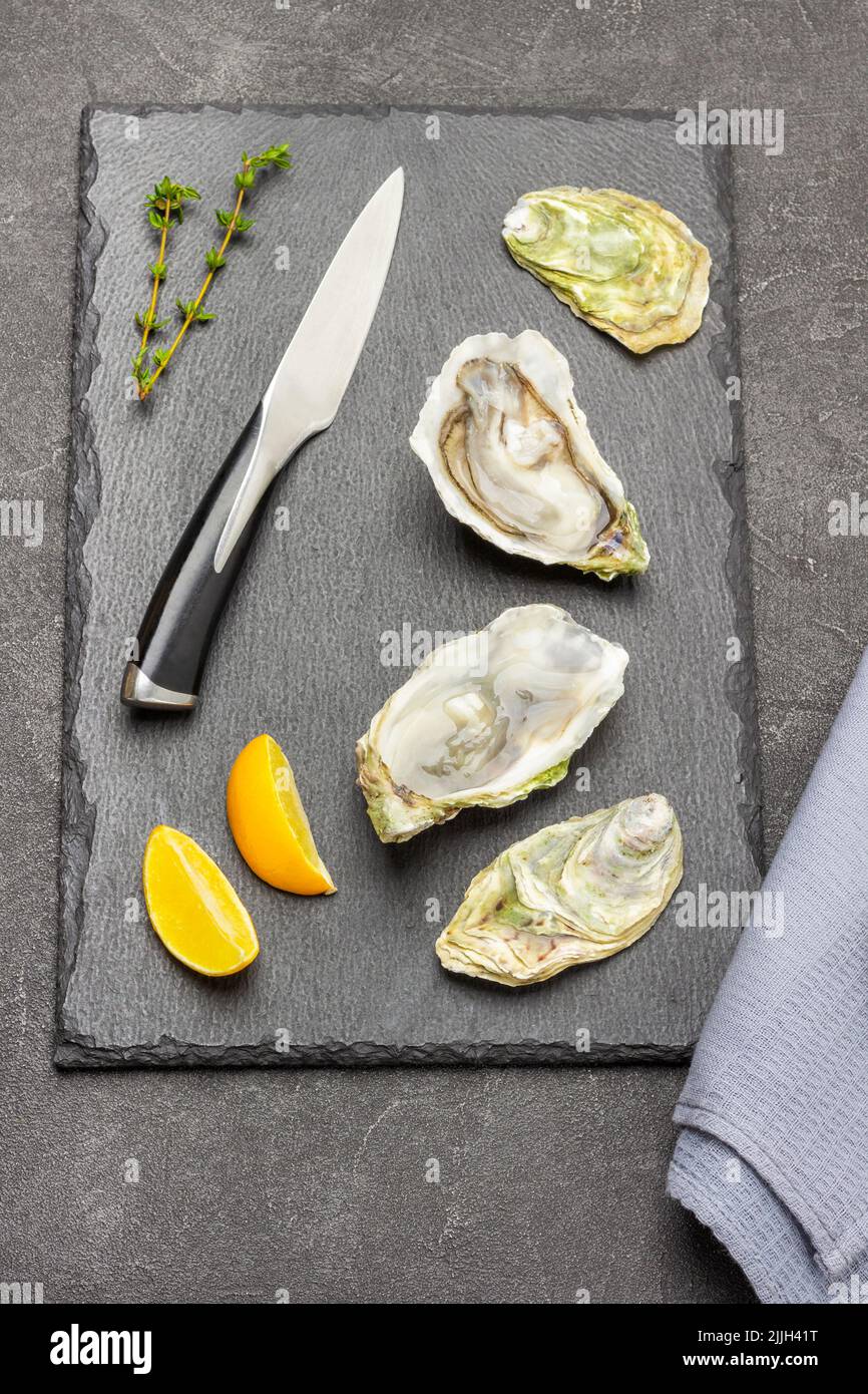 Opened clam shells, lemon slices, knife and sprigs of thyme on stone ...