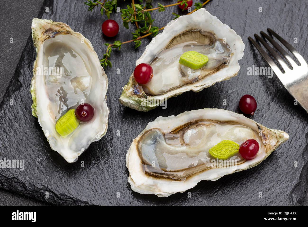 Opened clam shells and sprigs of thyme on stone board. Top view. Black ...