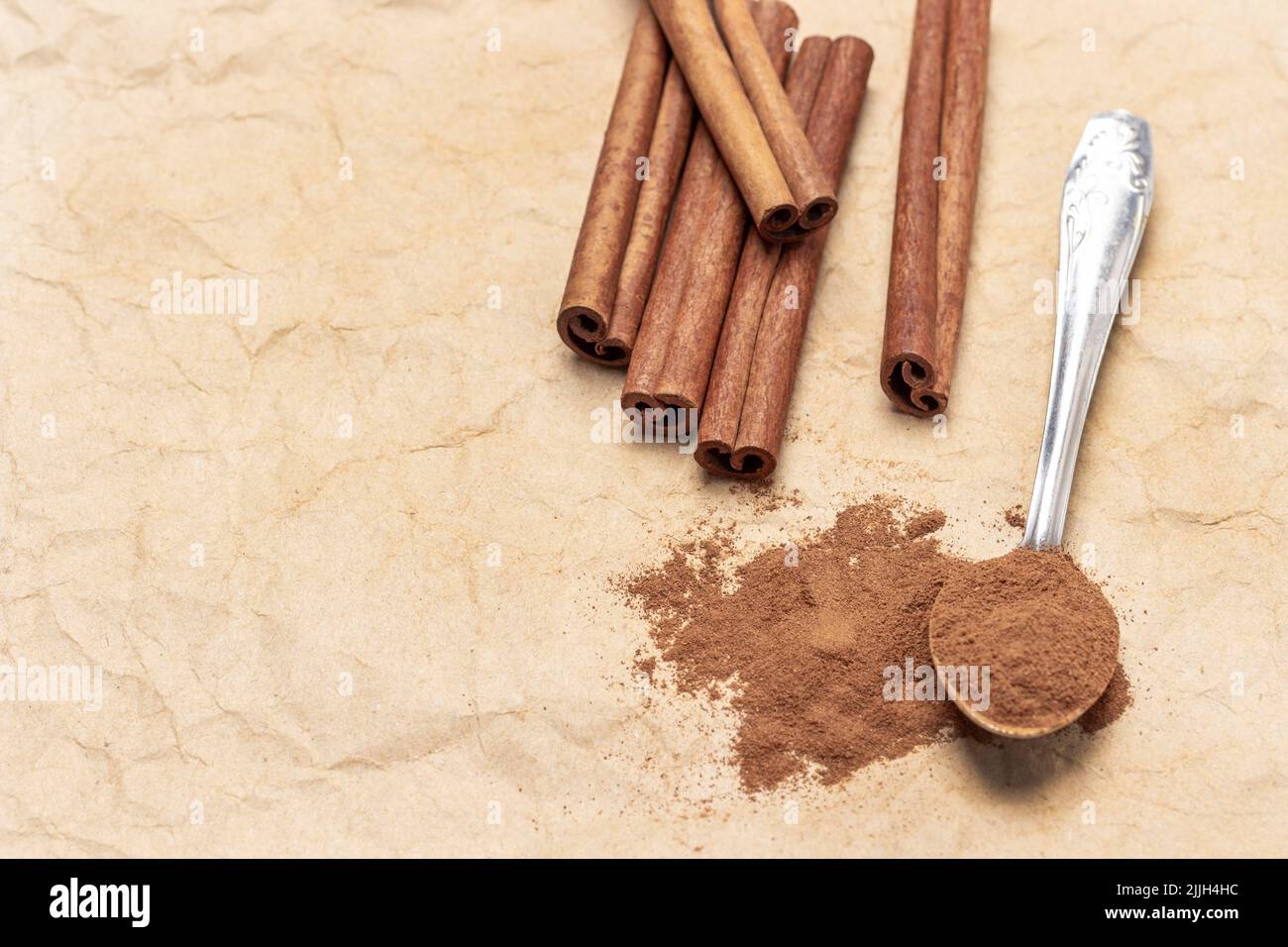 Ground cinnamon in metal spoon. Cinnamon sticks. Copy space. Top view ...