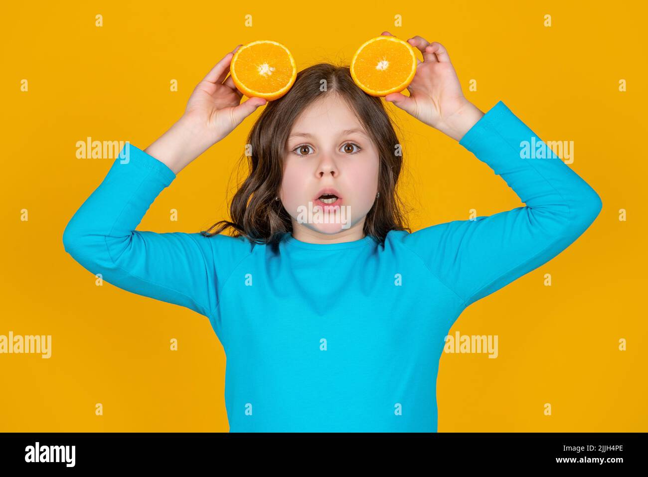 shocked teen girl hold orange fruit on yellow background Stock Photo ...