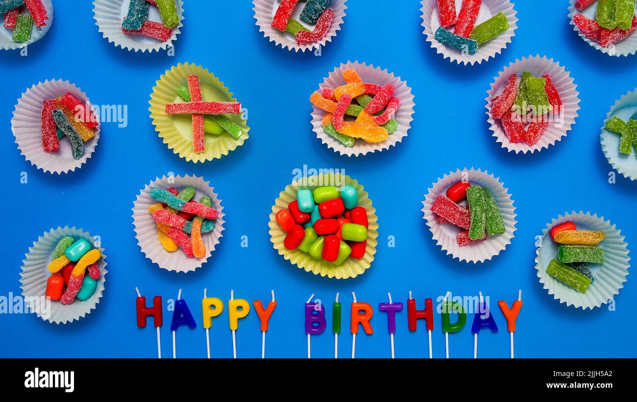 Various candy inside baking cups on blue background with happy birthday ...