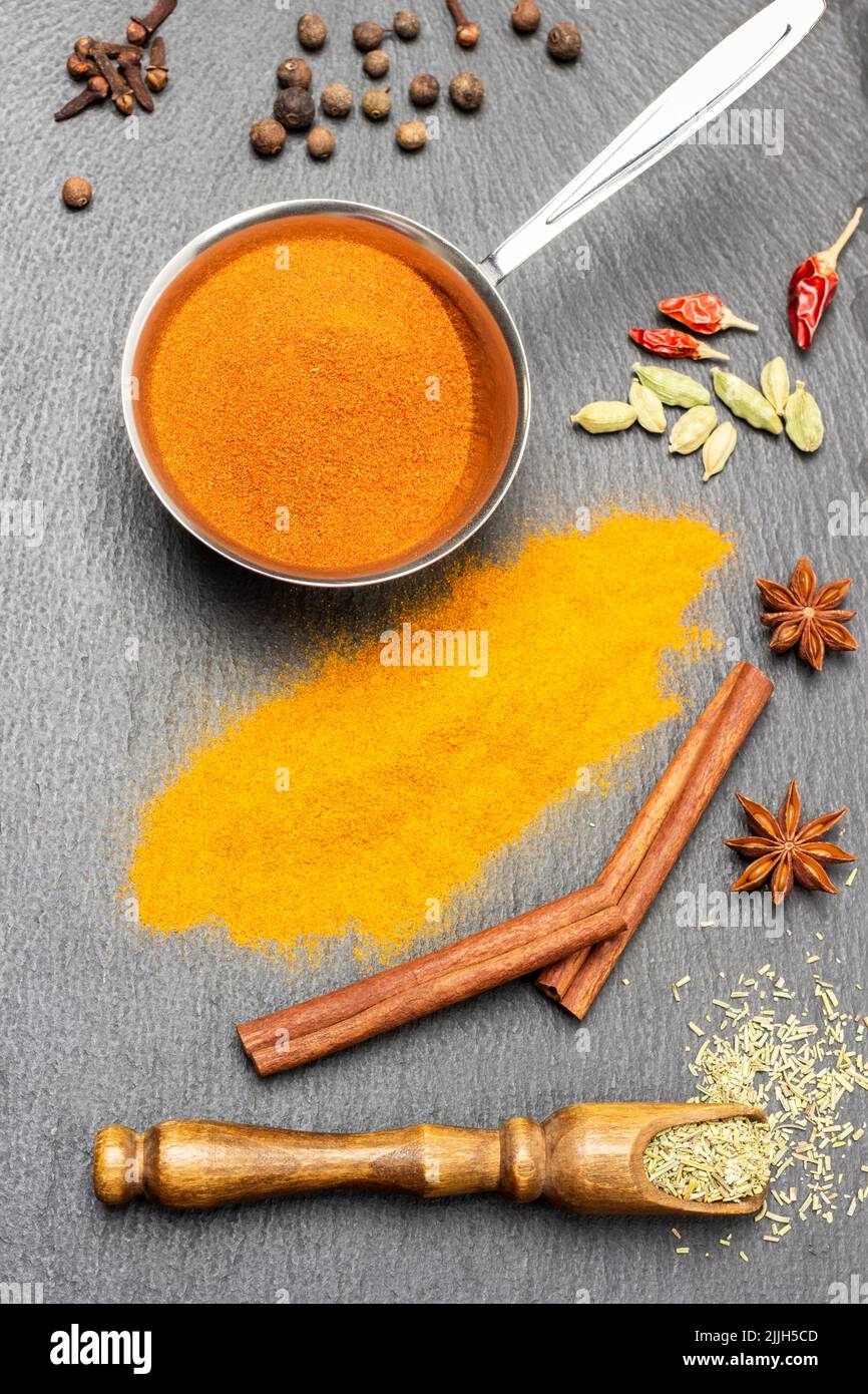 Ground turmeric in metal bowl and paprika on table. Cinnamon sticks ...