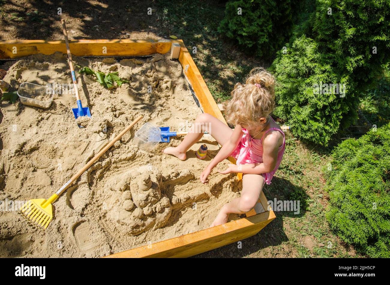 adorable blond girl having fun with sand in the playground Stock Photo ...