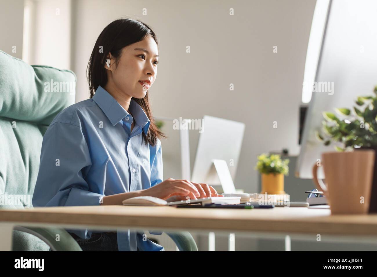 Japanese Business Lady Using Computer Wearing Earbuds Typing In Office ...