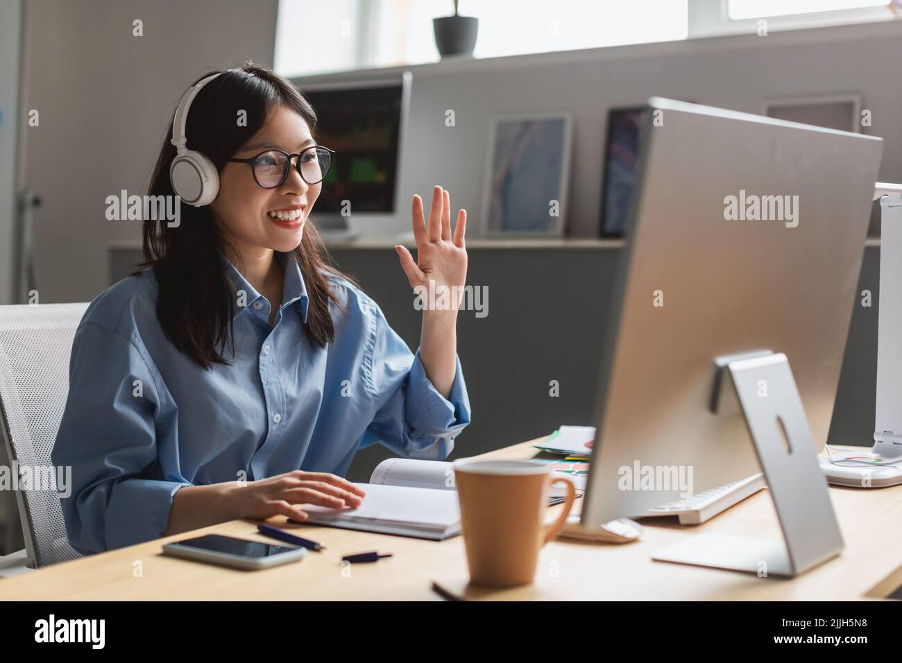 Japanese Woman Video Calling Waving Hand To Computer In Office Stock ...
