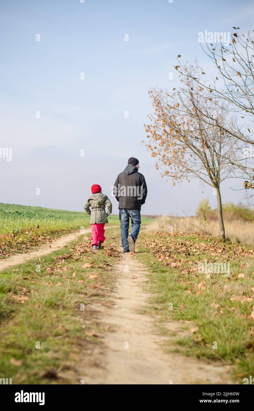father and daughter back view going for walk alone in nostalgic fall ...
