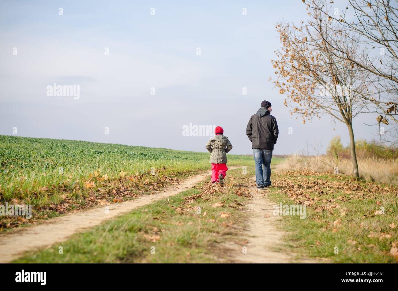 father and daughter back view going for walk alone in nostalgic fall ...