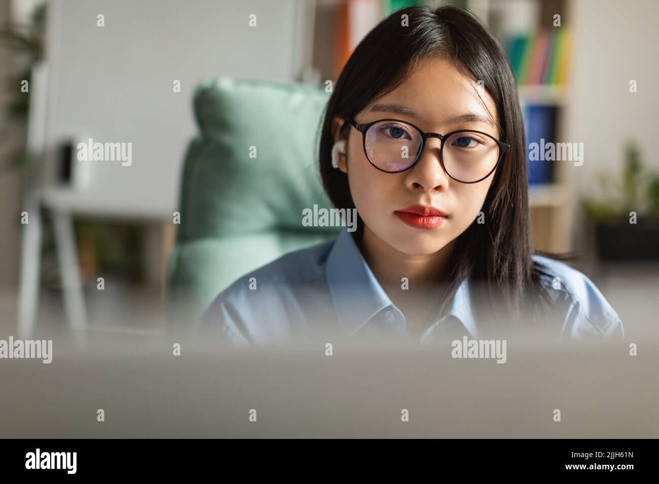 Japanese Business Female Wearing Earbuds Using Computer At Workplace ...