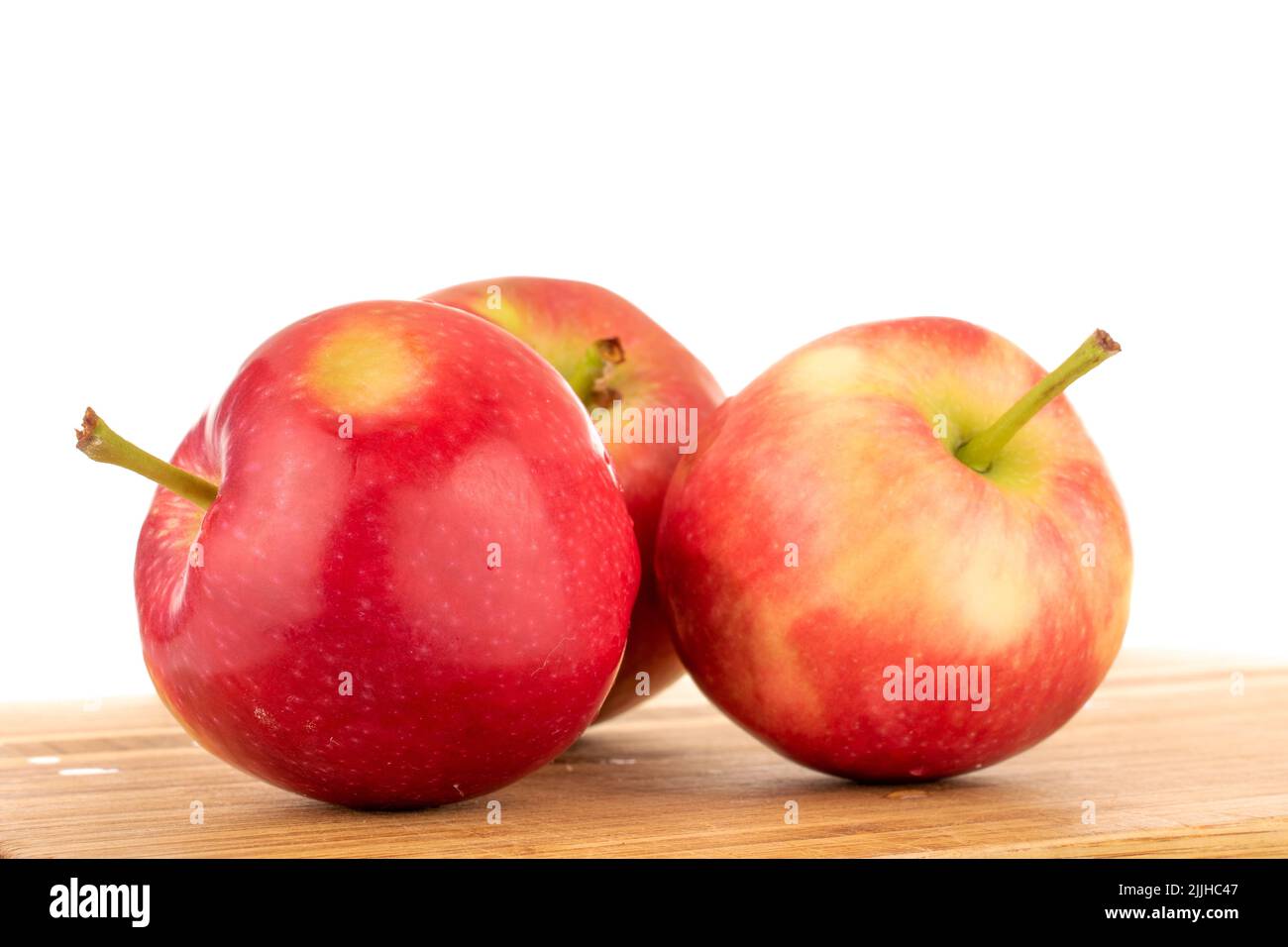 Three red sweet apples on a kitchen board, close-up, on a white ...