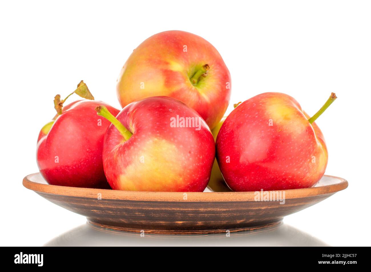 Several ripe sweet red apples on a clay dish, close-up, isolated on a ...