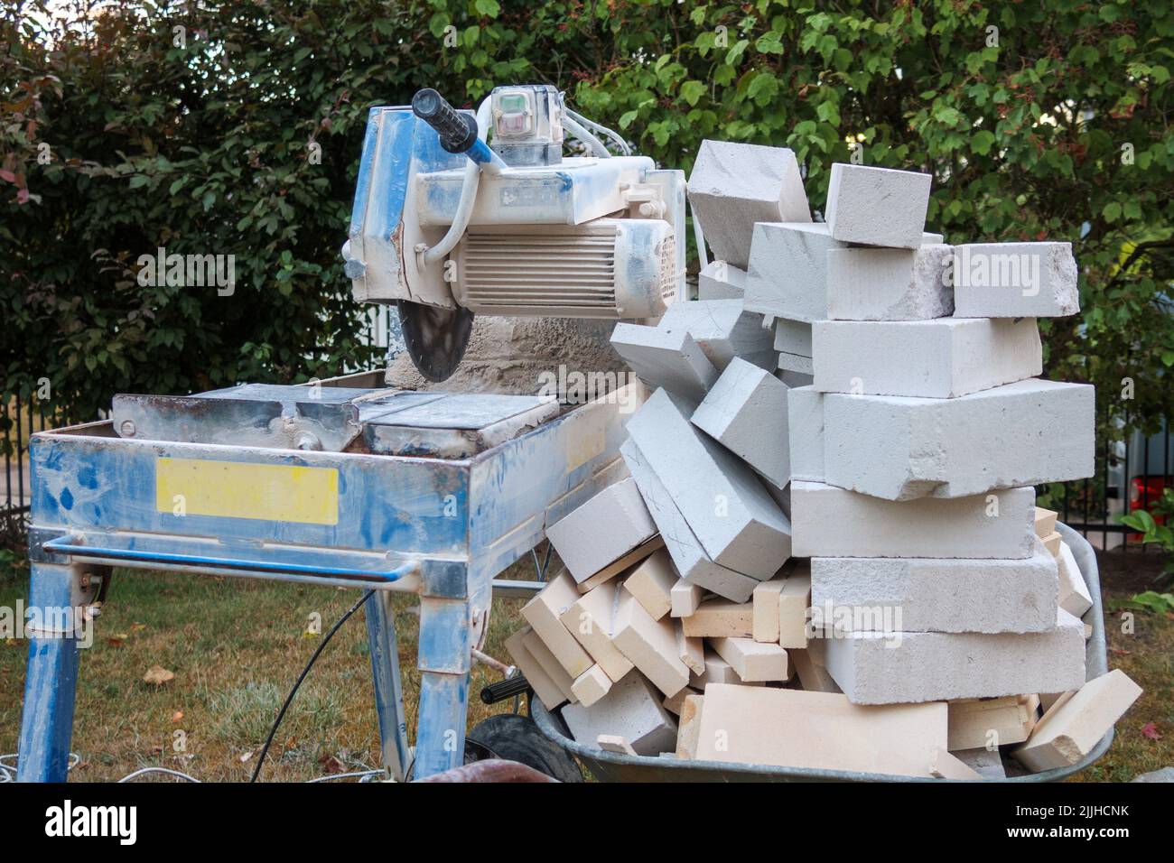 Next to a circular saw for stones there is a wheelbarrow with stone ...