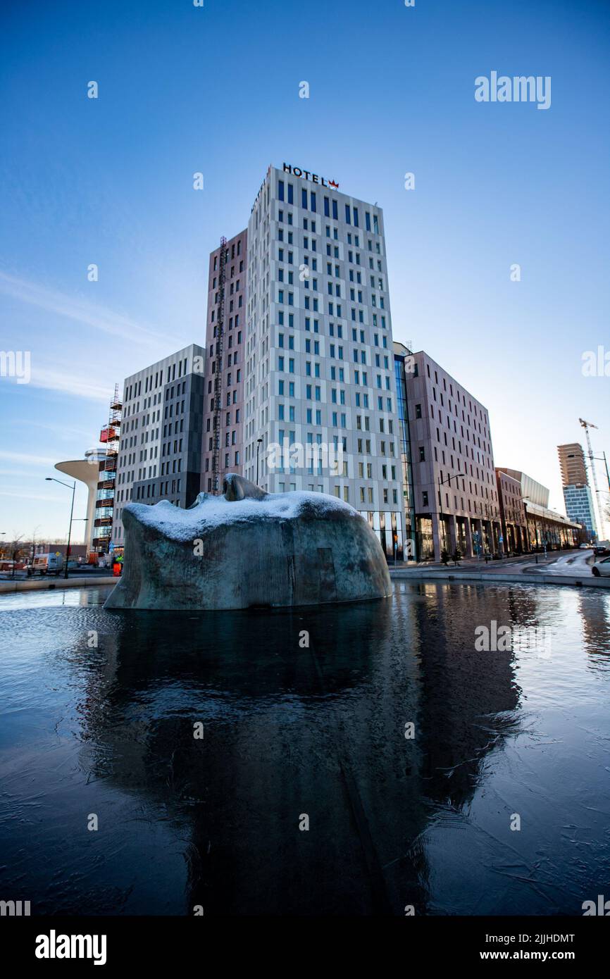 A view of the Malmo Arena Hotel with a fountain and artwork in front of ...