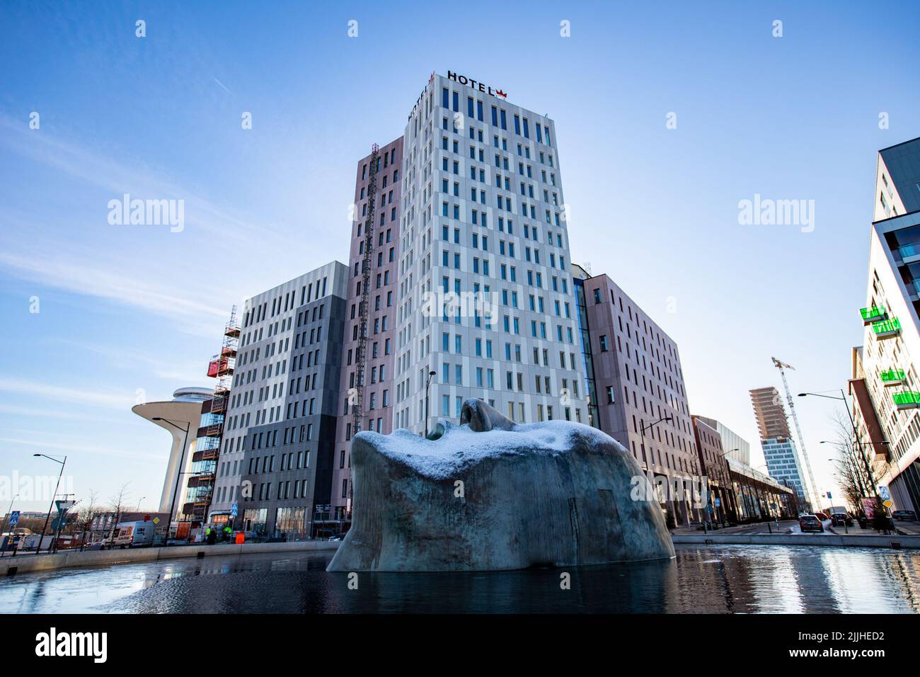 A view of the Malmo Arena Hotel with a fountain and artwork in front of ...