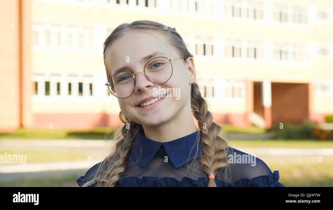 A teenage girl wearing glasses in front of a school Stock Photo - Alamy