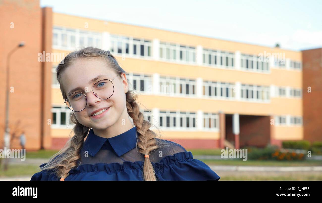 A teenage girl wearing glasses in front of a school Stock Photo - Alamy