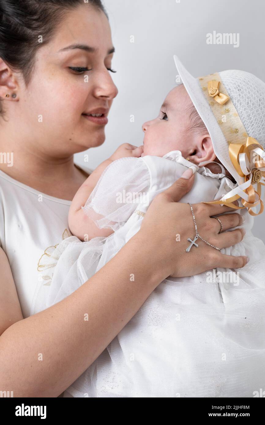 beautiful young latin mother, holding her baby with a silver chain ...