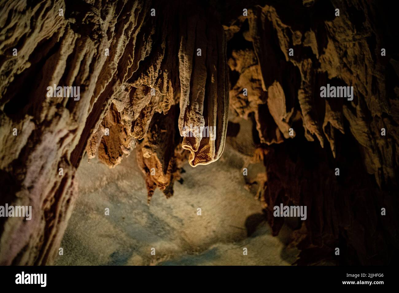 A closeup view of mineral stalactites hanging from the ceiling of the ...