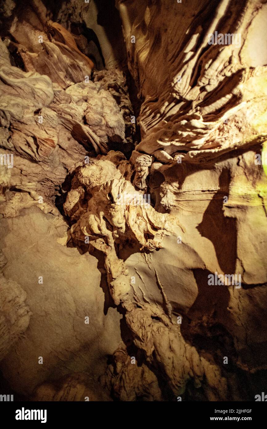 A vertical closeup of long mineral stalactites hanging from the ceiling ...