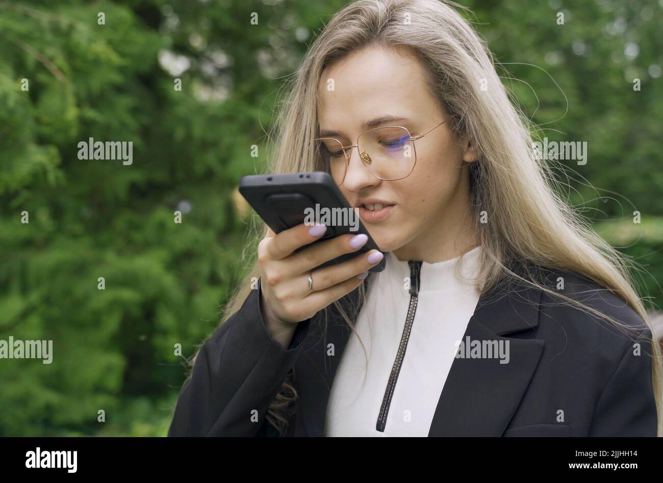 Happy girl records an audio message on a smartphone. Calls on the ...