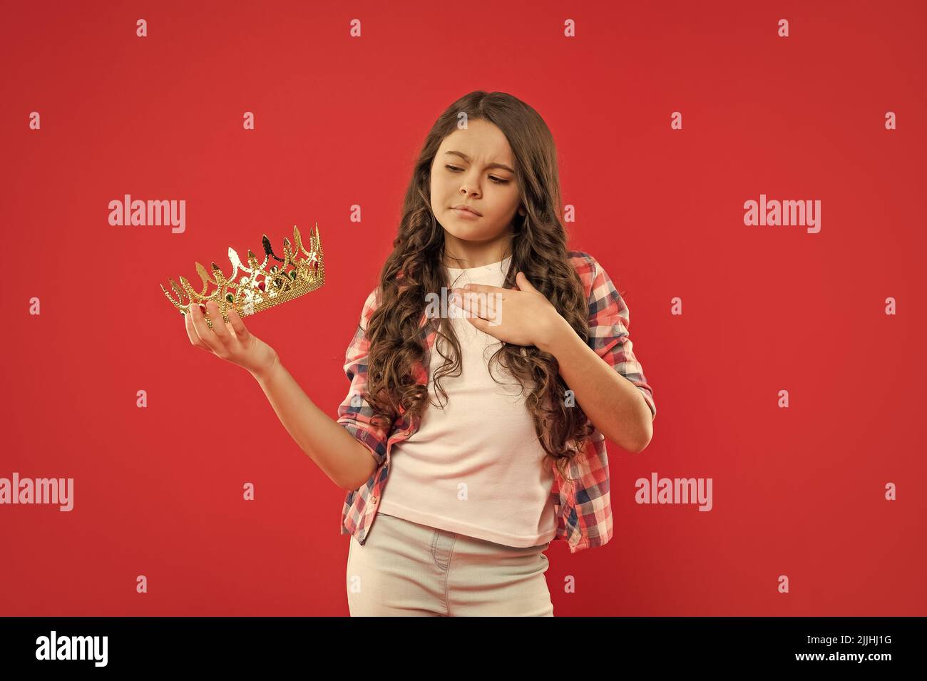 arrogant child with curly hair hold queen crown on red background ...
