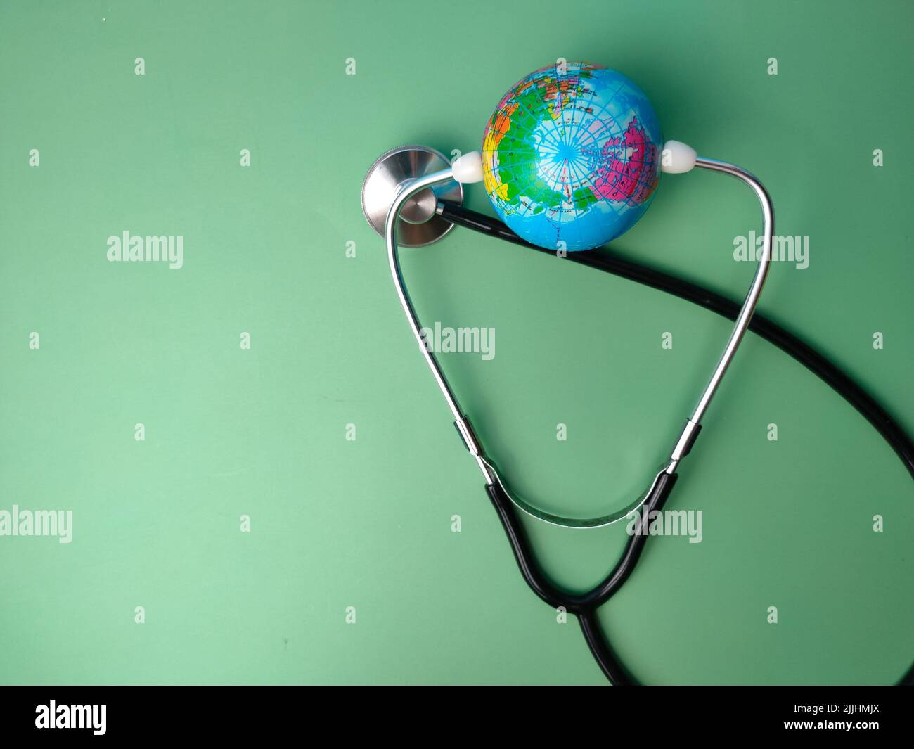 A 3D rendering of a stethoscope and earth globe on a green background ...