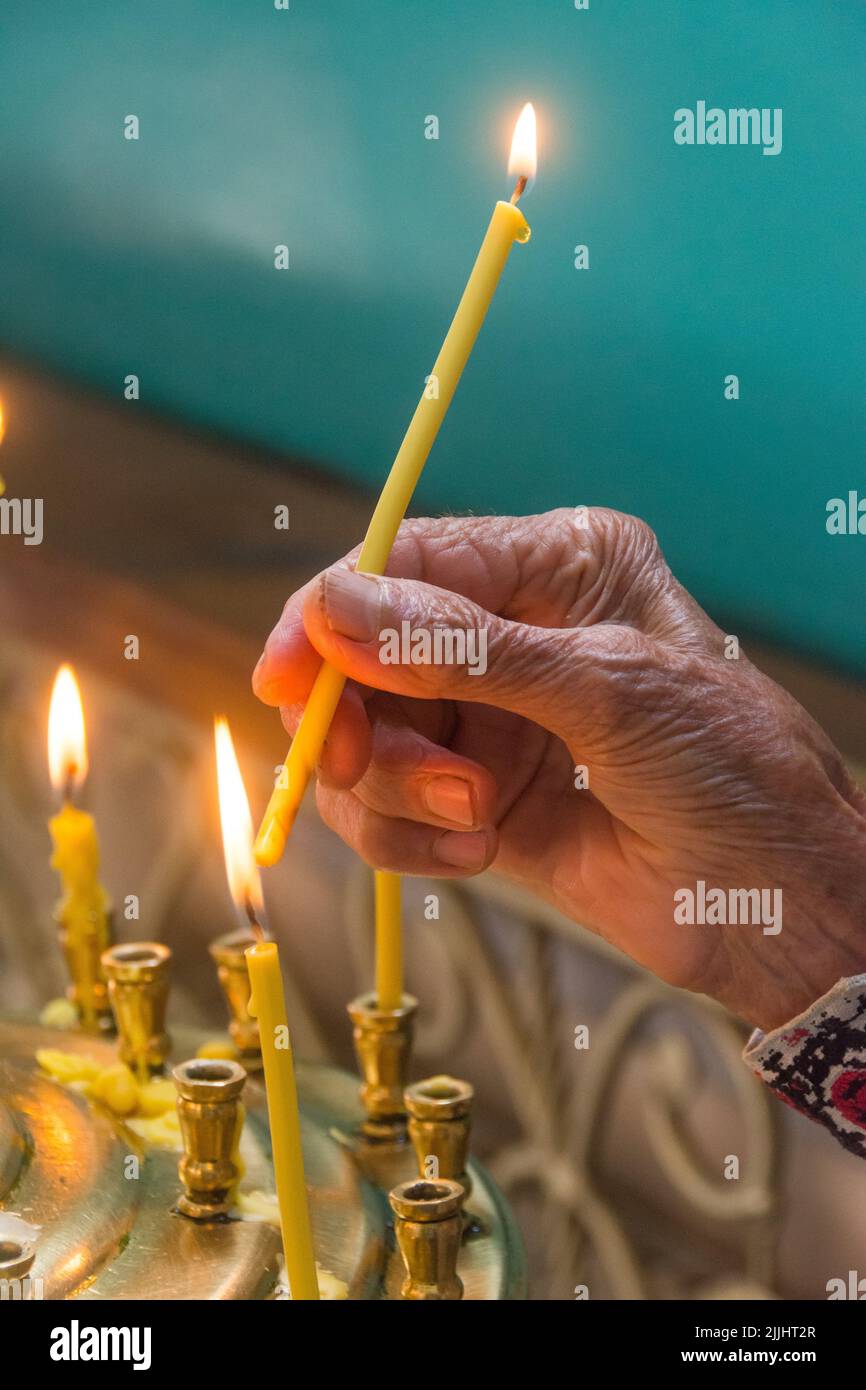 A vertical shot of a female hand putting a candle in the candelabra ...