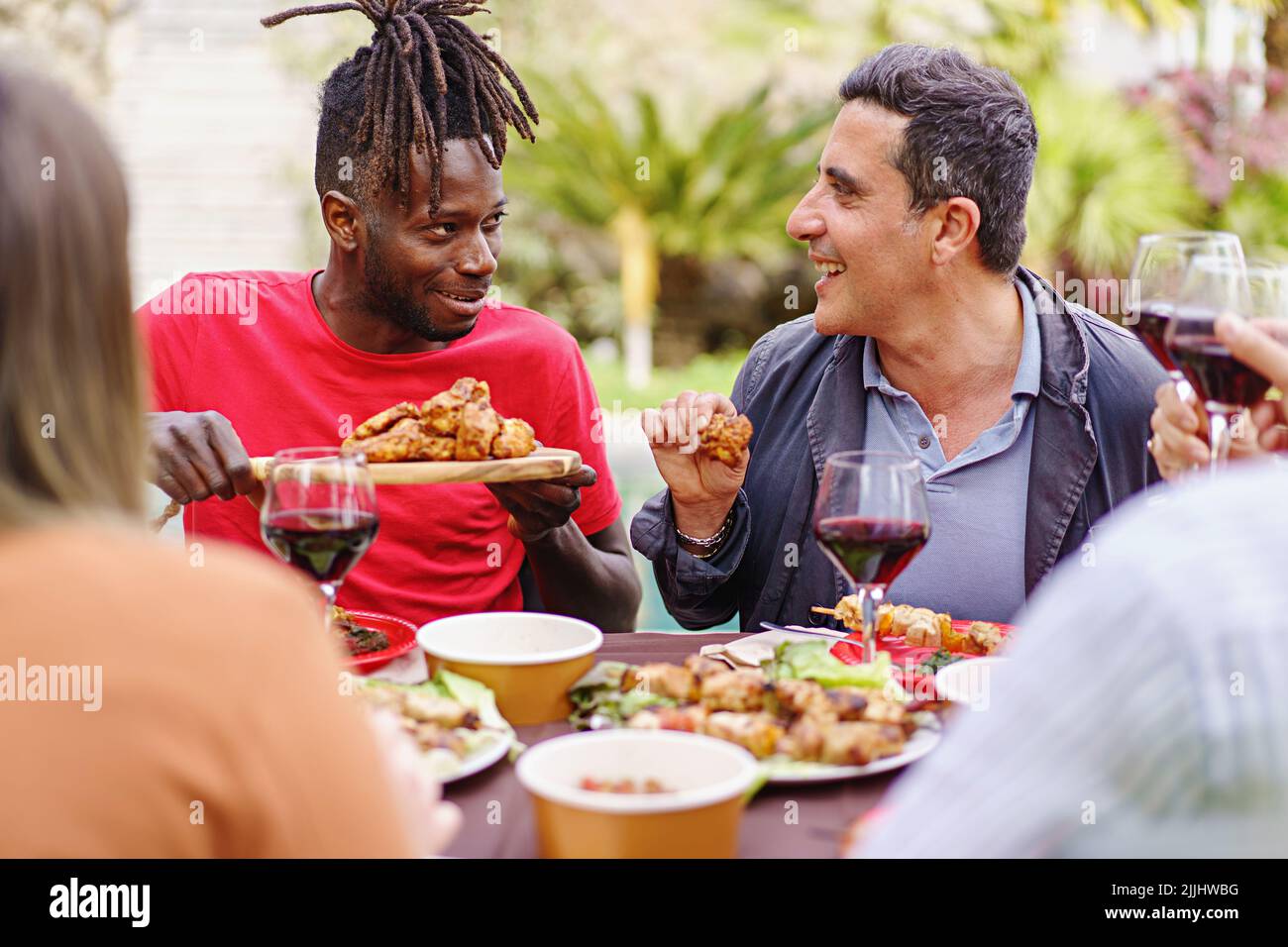 Friends eating chicken wings outdoors- happy people dining and talking ...