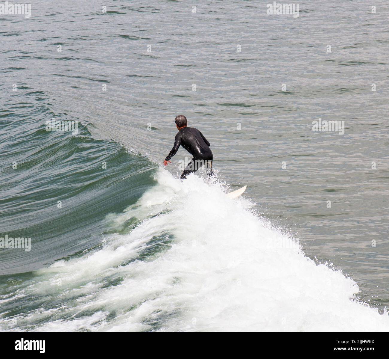 Rear view of a overhead view of a man surfing a wave next to the ...