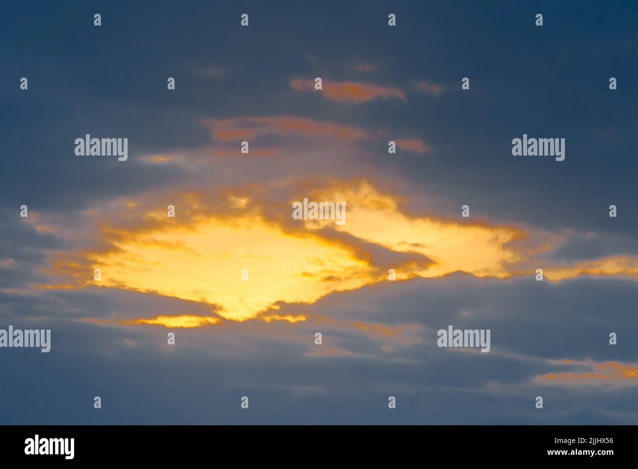 Light spot orange sunset through dark rain clouds storm beam light sky ...