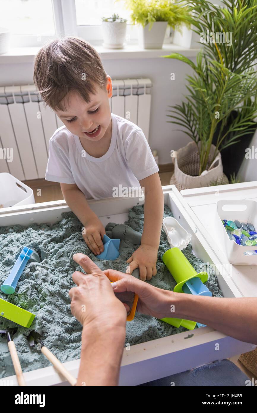 Overjoyed male kid playing kinetic sand early development education ...