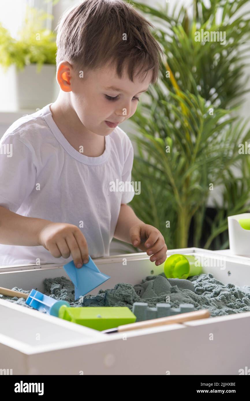 Overjoyed male kid playing kinetic sand early development education ...