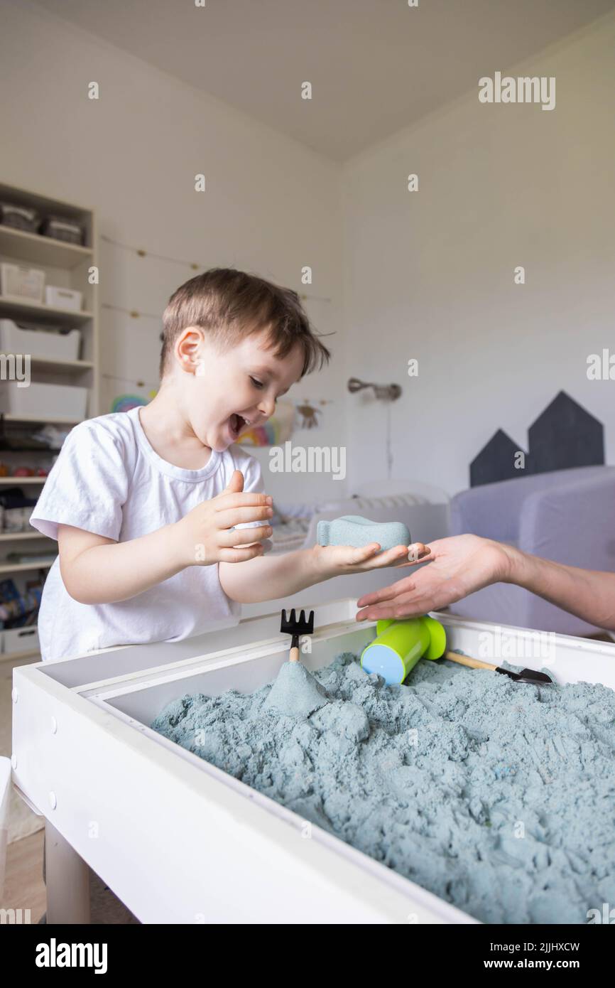 Overjoyed male kid playing kinetic sand early development education ...