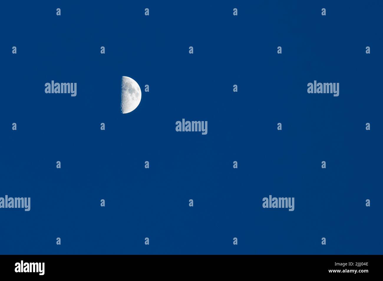 Crescent moon small against dark blue evening sky natural light ...