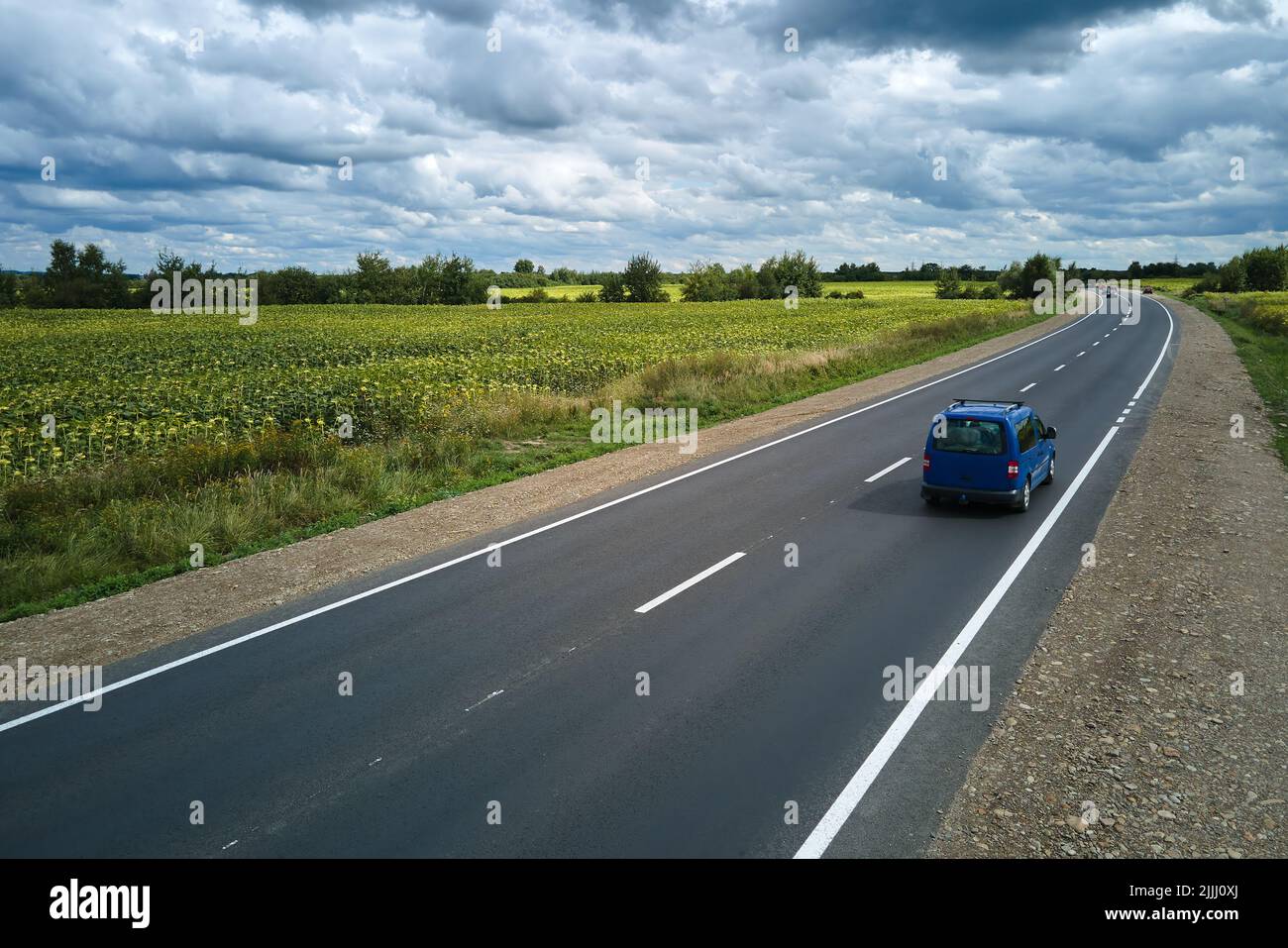 Aerial view of intercity road between green agricultural fields with ...