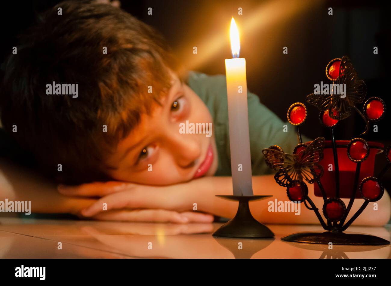 Child looking at a lit candle lying on the floor of the house. Salvador ...