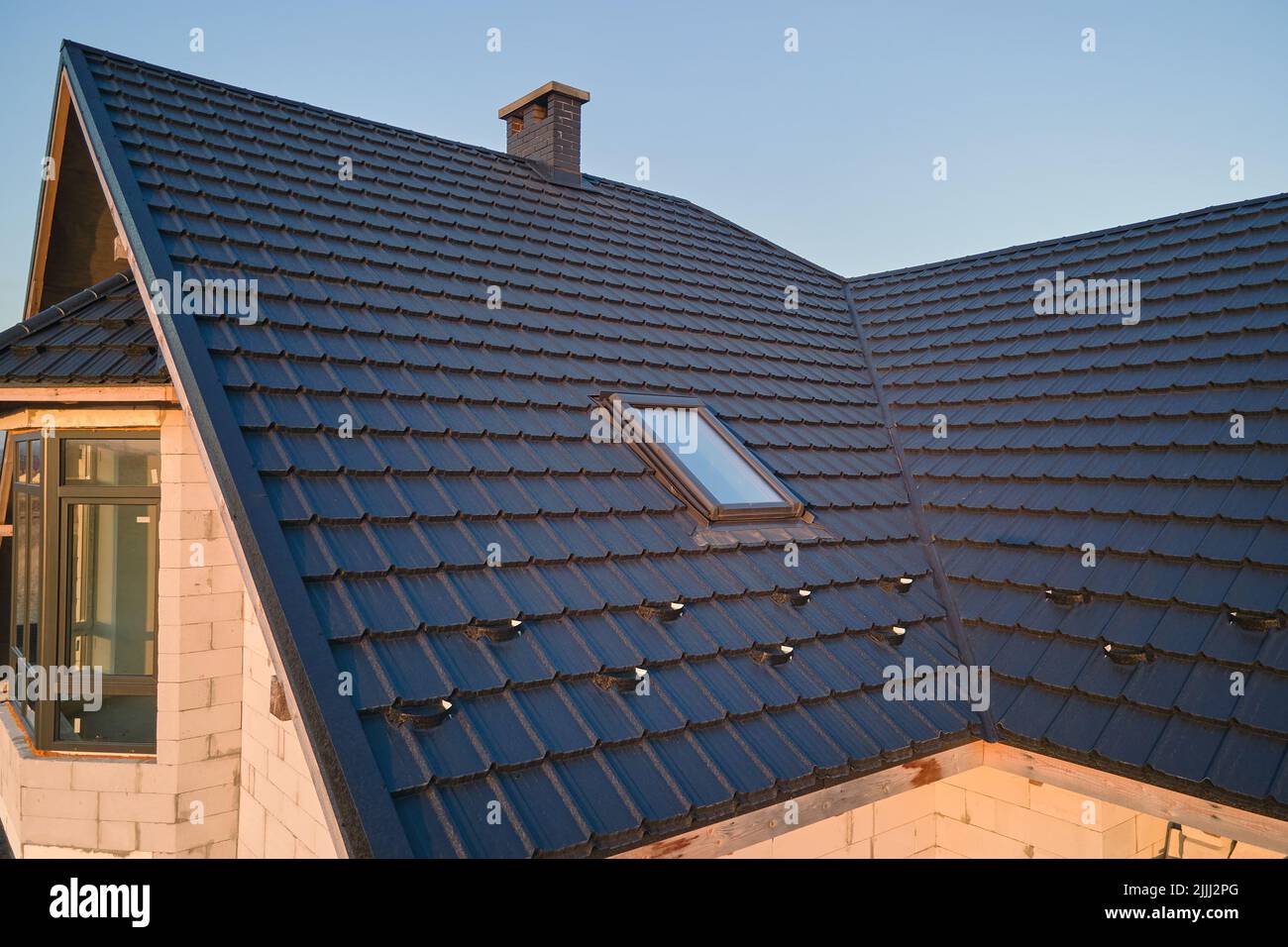 Closeup of attic window on house roof top covered with ceramic shingles ...