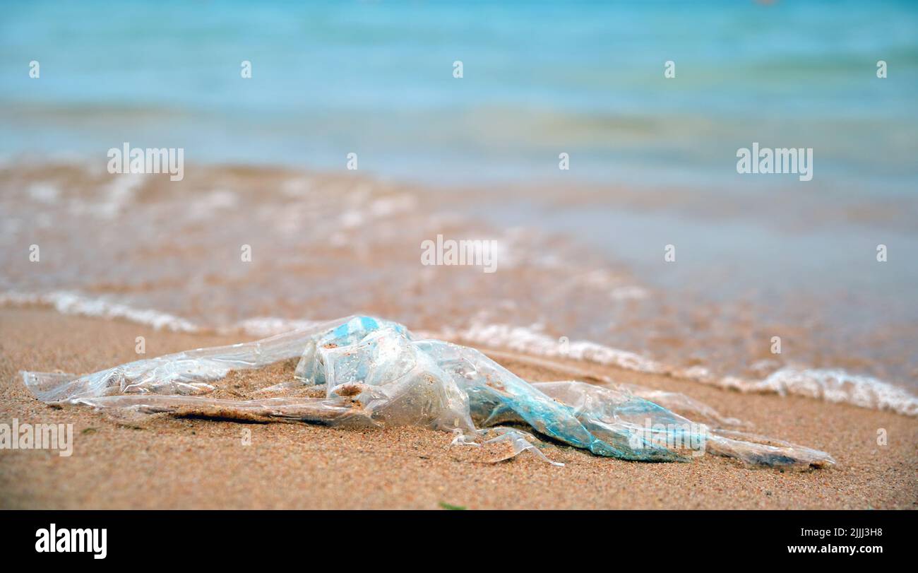 Left behind plastic bag garbage on sandy beach. Empty used dirty litter ...