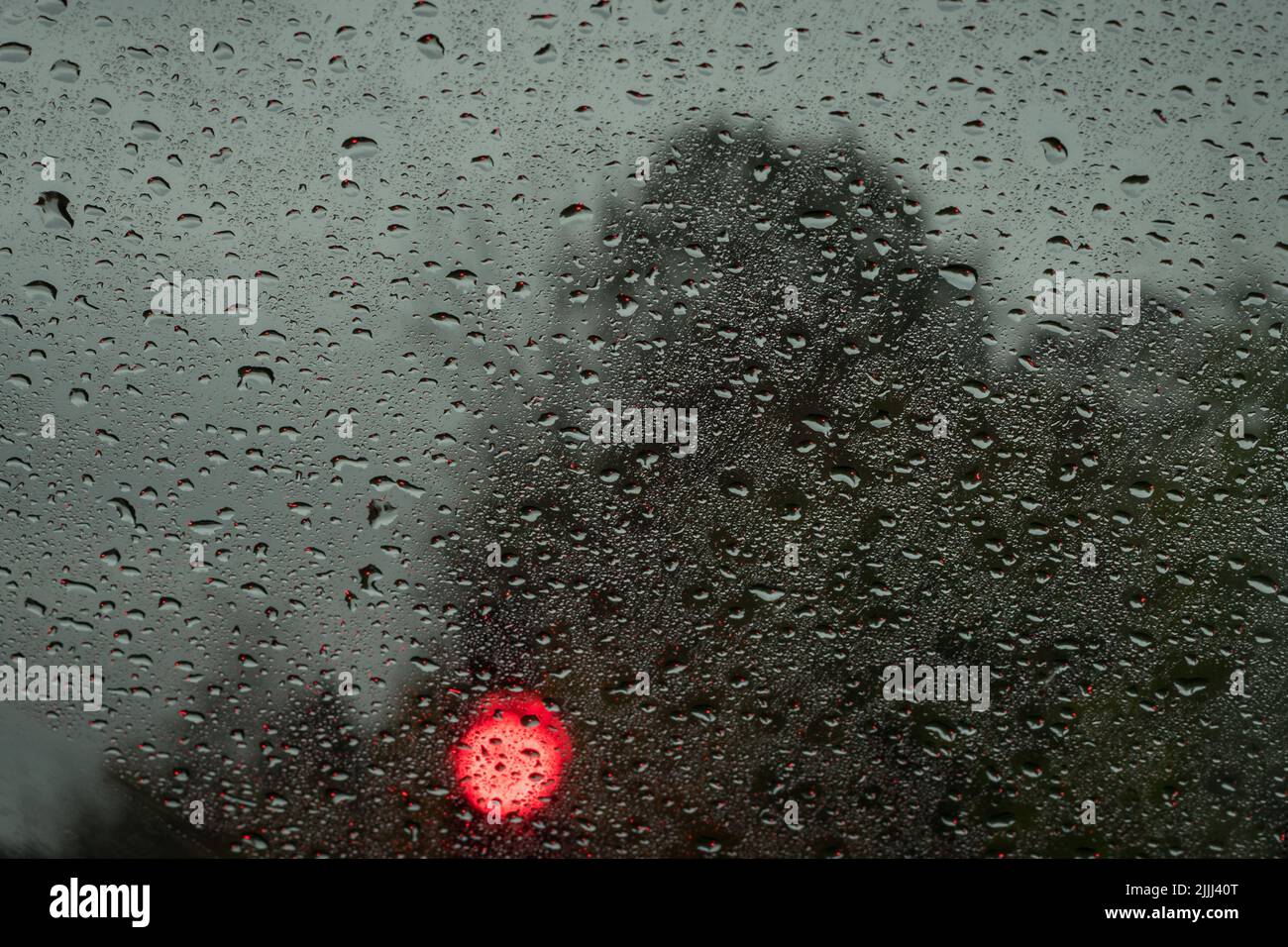 A blurred red traffic light captured through a rainy windshield Stock ...