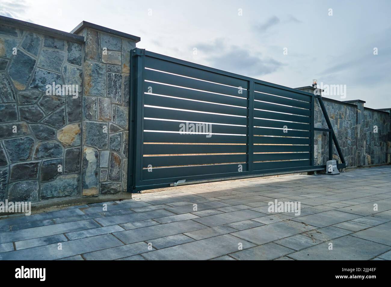 Wide automatic sliding gate with remote control installed in high stone ...