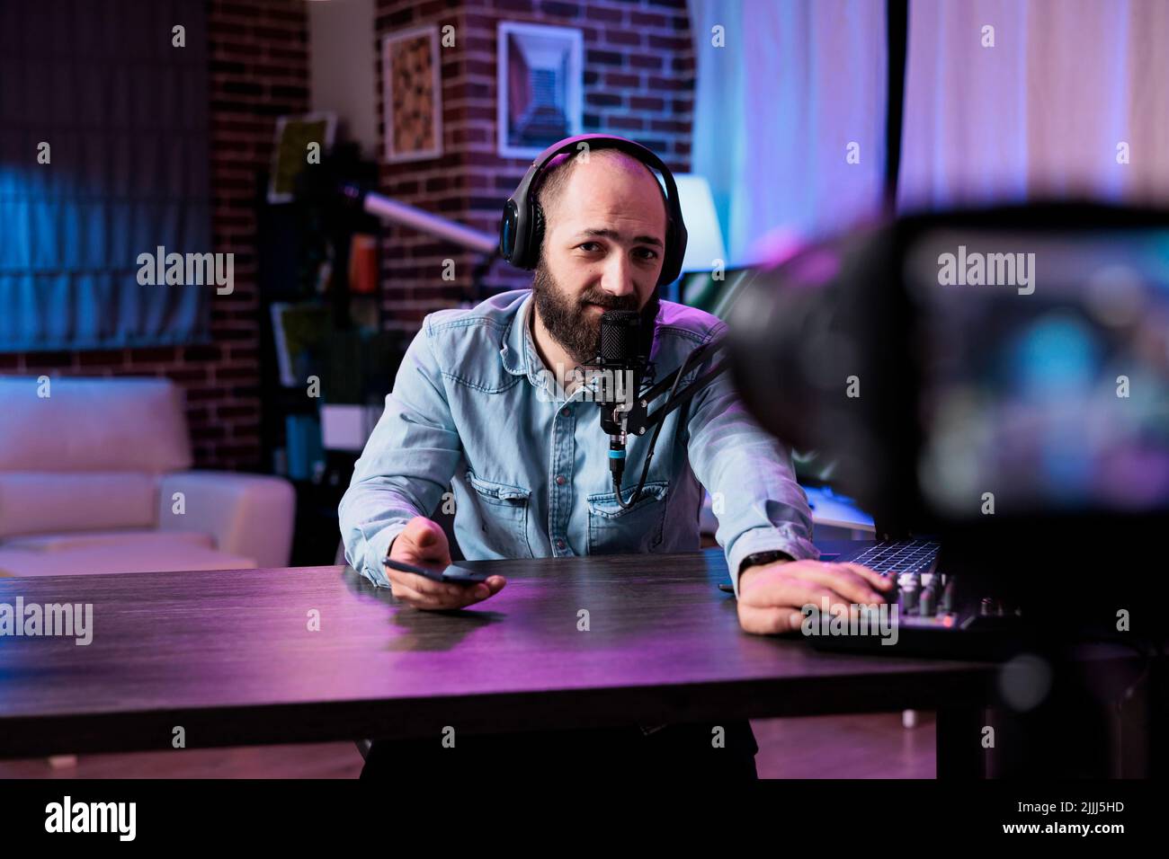 Male influencer filming vlog with podcast equipment in studio ...