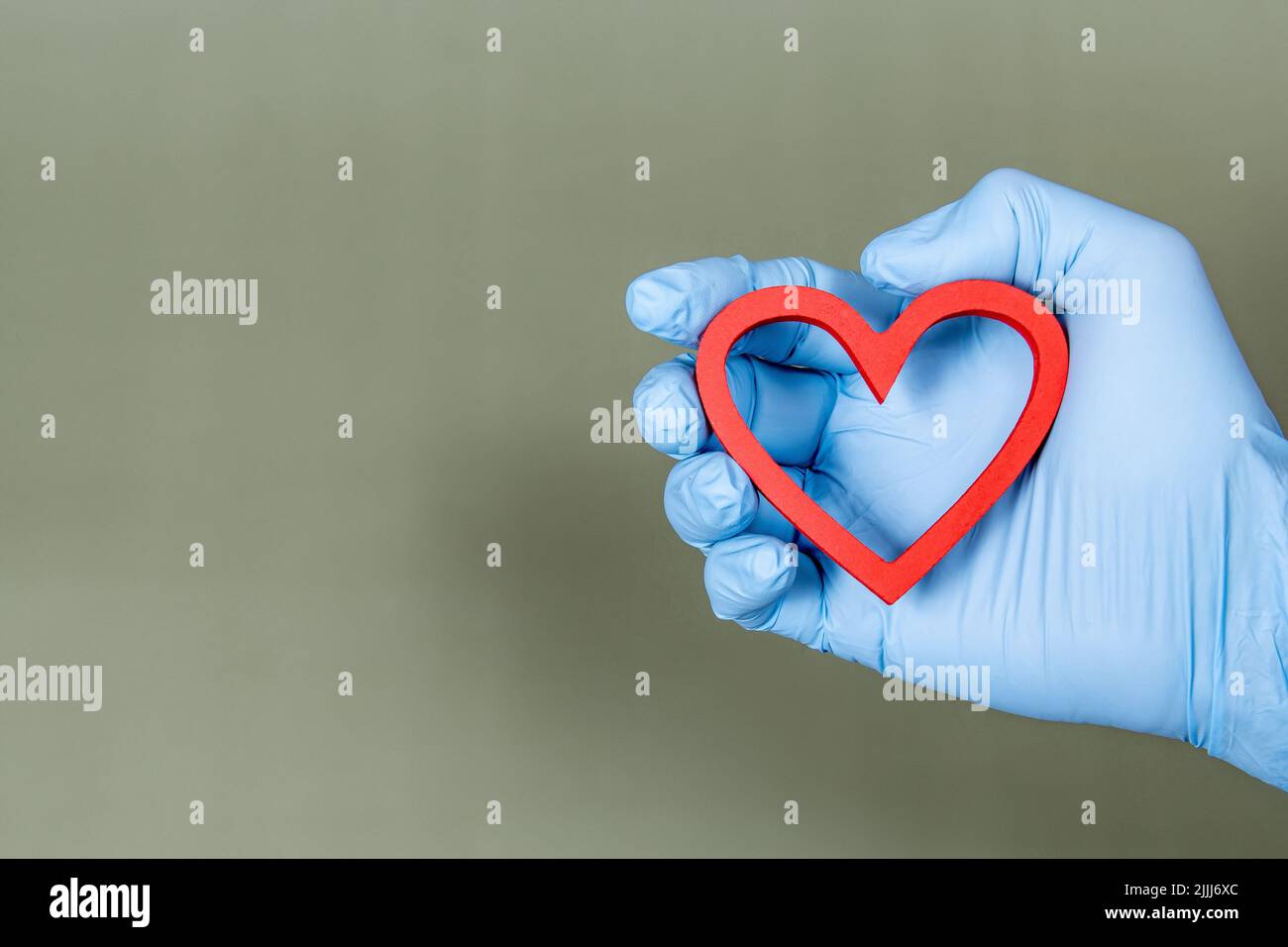 Cirurgical gloved hand holding a heart shape Stock Photo - Alamy