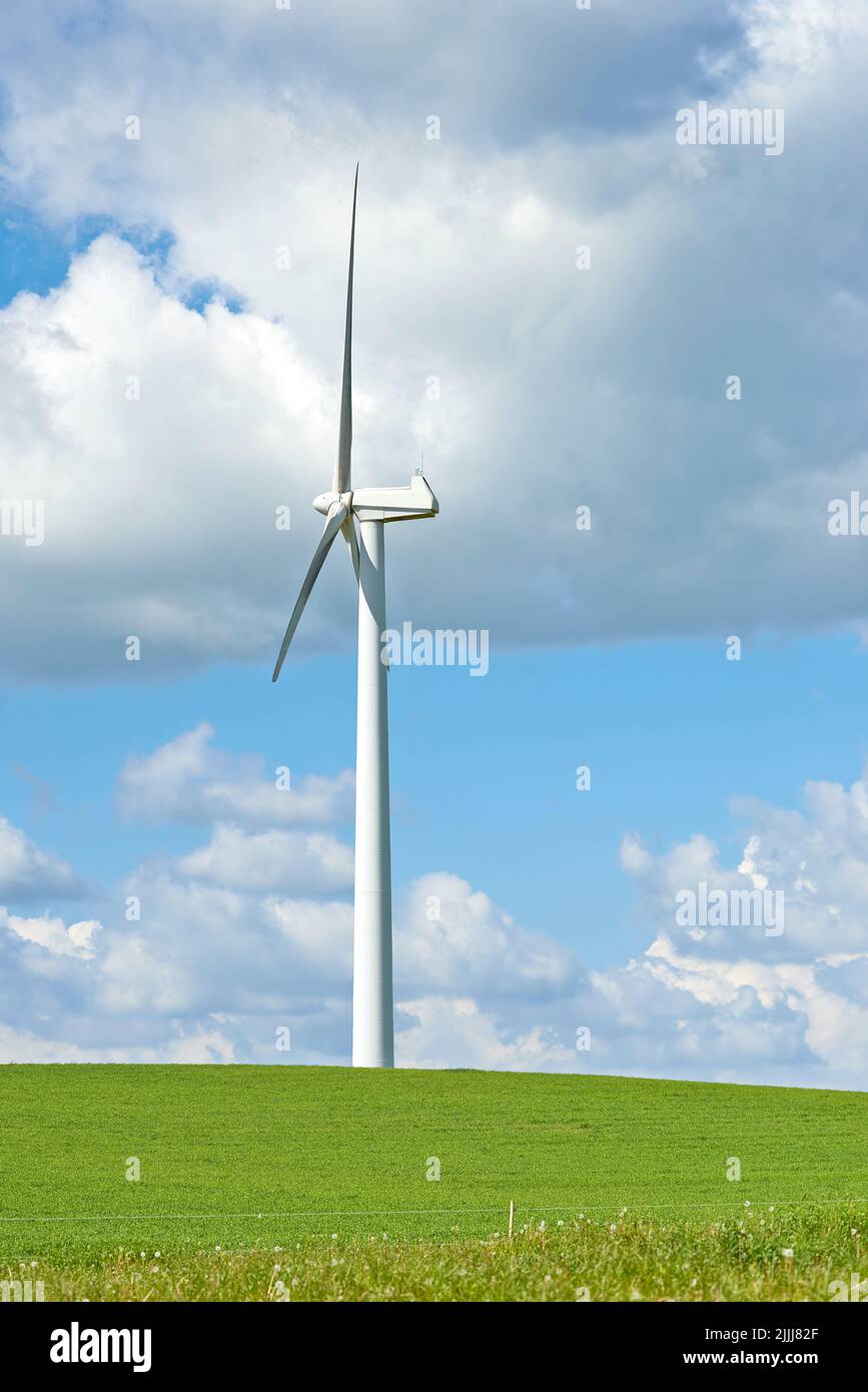 Windmill. A windmill on a green hill against cloudy blue sky with copy ...
