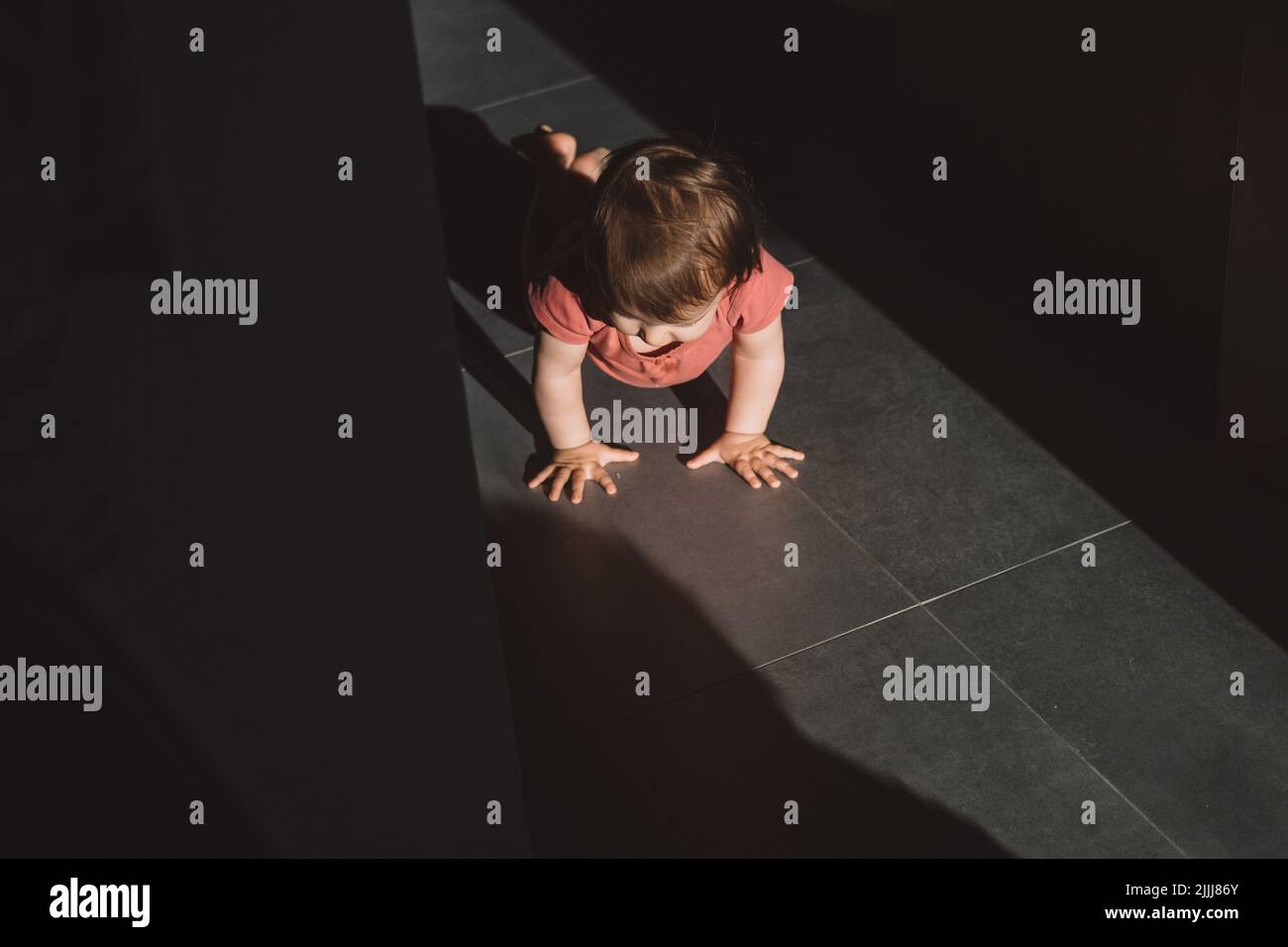 View from above of a baby girl crawling over floor, playing. Baby care ...