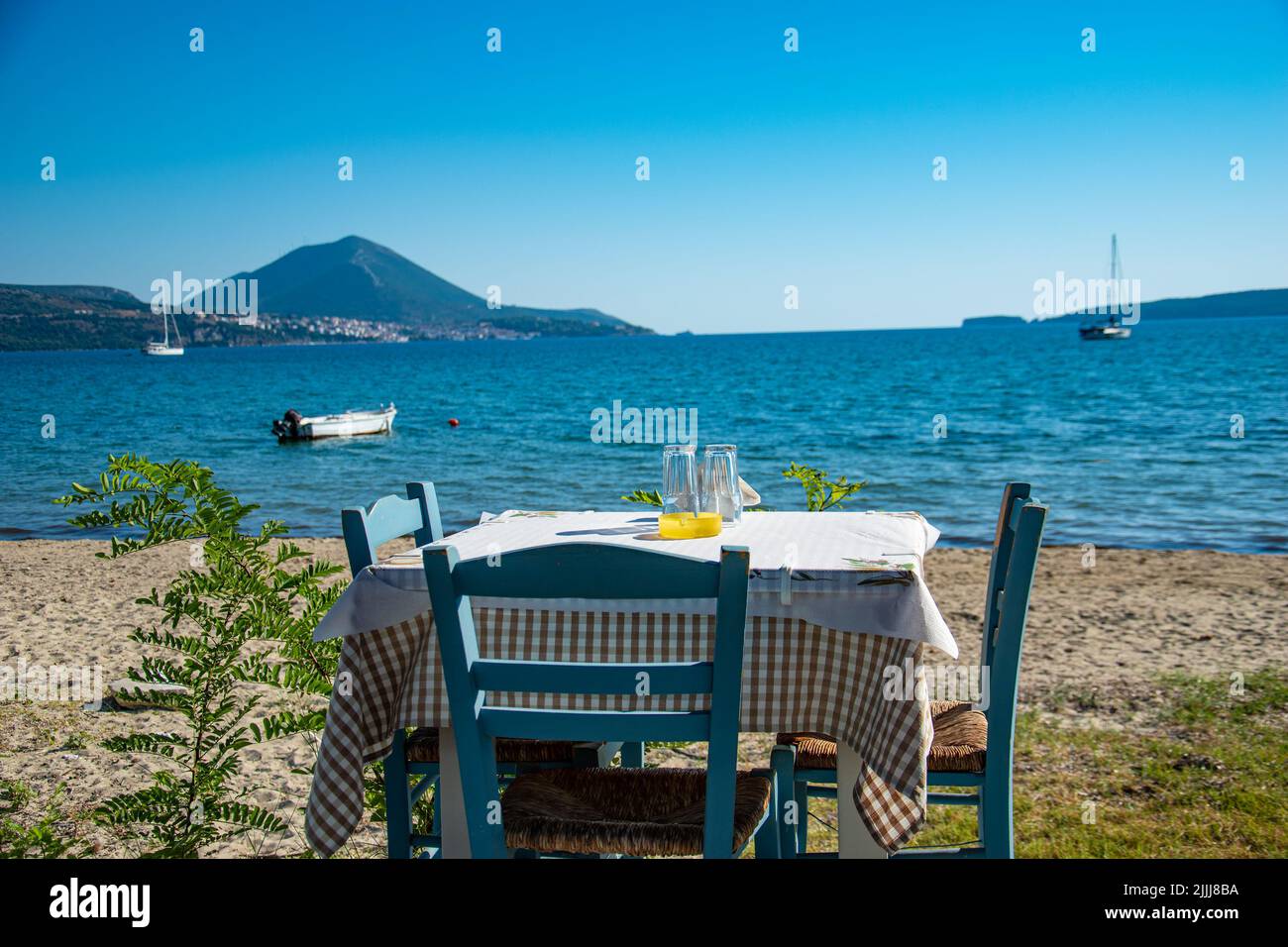 Typical Greek seaside tavern table with wooden chairs by the sea coast ...