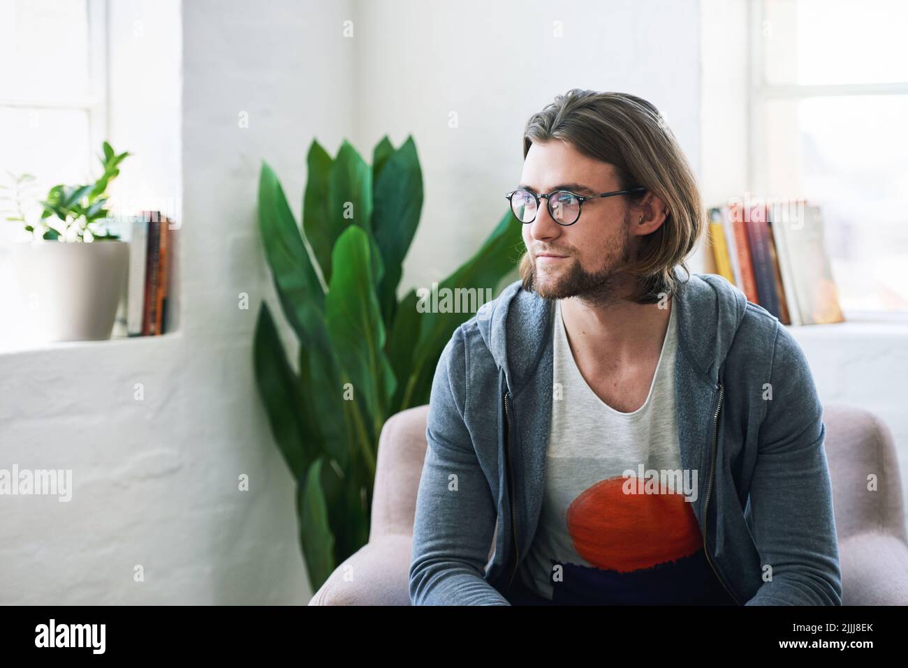 Young man looking out window thinking sitting on sofa at home Stock ...